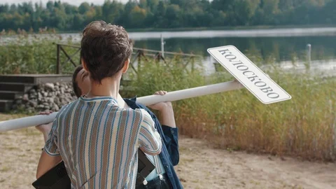 Two men stand on sandy shore looking dow... | Stock Video | Pond5