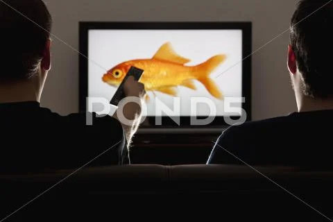 Two Men Watching Television With One Using A Remote Control - Stock ...