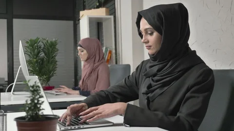 Two Muslim girls in hijabs work in the o... | Stock Video | Pond5