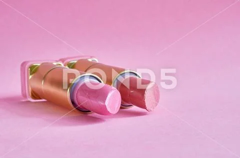 Photograph: Two old used lipstick tubes lie on a pink background #138077692