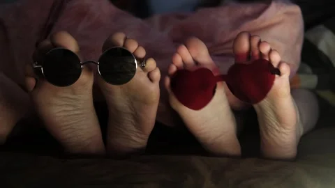 Two pairs of female feet in bed. Sunglas... | Stock Video | Pond5