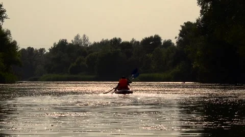 Two people rowing along the river with p... | Stock Video | Pond5