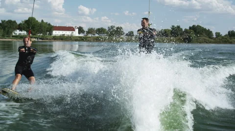 two people wakeboarding behind a boat | Stock Video | Pond5