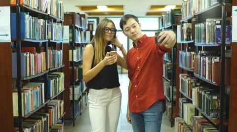 two students taking selfies in the libra... | Stock Video | Pond5