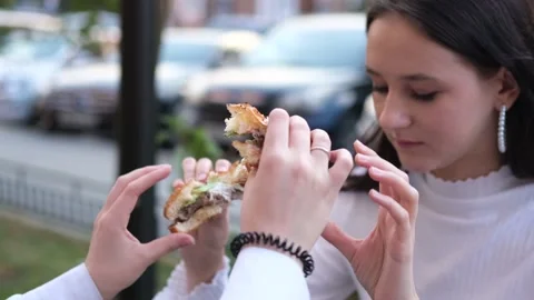 Two teenage friends biting the same hamb... | Stock Video | Pond5