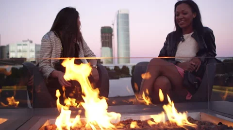 Two women sit in front of a fire pit on ... | Stock Video | Pond5