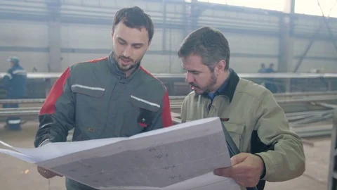 Two workers look at the drawing at the f... | Stock Video | Pond5