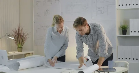 Two young designers unfold the drawings ... | Stock Video | Pond5