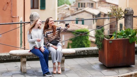 Two young women are sitting on the bench... | Stock Video | Pond5