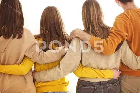 Photograph: Unrecognizable friends hugging each other Back view of ...
