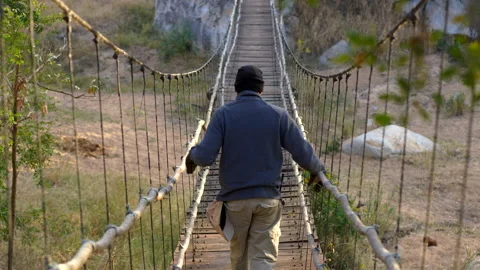 Unrecognizable man crossing rope bridge.... | Stock Video | Pond5