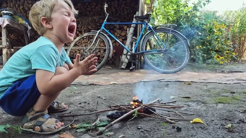 Upset child crying by the fire. Concepts... | Stock Video | Pond5