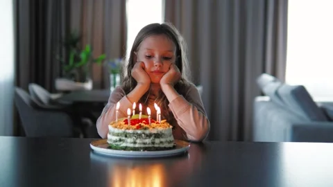 Upset female kid sitting at birthday cak... | Stock Video | Pond5