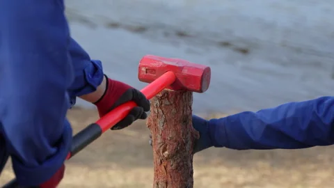 Using a hammer to hit wooden piles and i... | Stock Video | Pond5