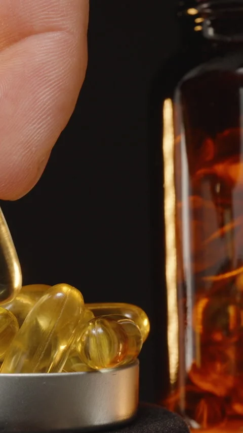 Vertical video. Hand Dropping an Omega 3... | Stock Video | Pond5