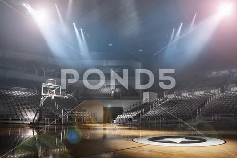 View of empty basketball arena with dramatic lighting from on the court ...