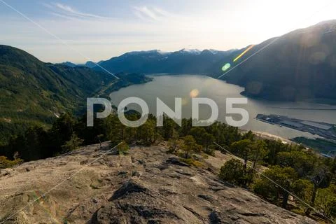 View point from cliff above valley and bay with mountains and clouds ...