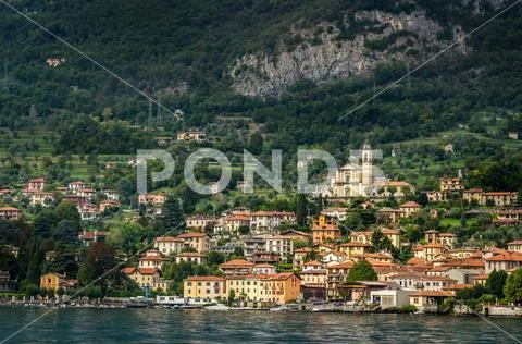 View of village in forest in Lake Como from ferry at sunset, Lake Como ...