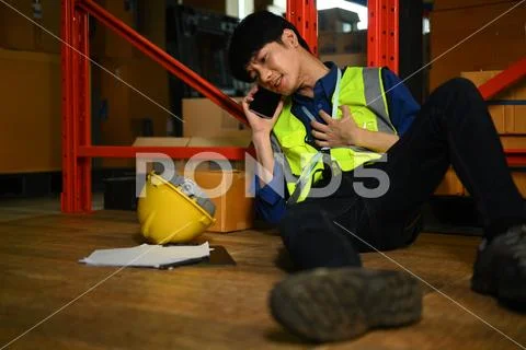 Warehouse worker making an emergency call, asking for first aid team ...