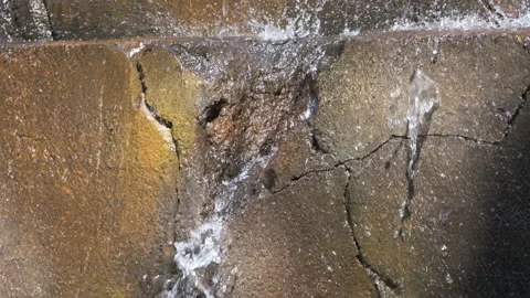 Water falling down from a stone wall in ... | Stock Video | Pond5
