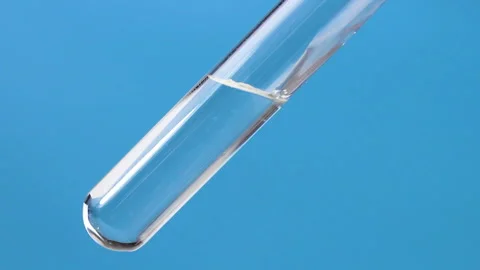 Water fills glass test tube on blue back... | Stock Video | Pond5