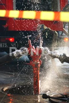 Water splashes from the fire hose and hydrant connections. Firefighters ...