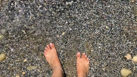 waves of a sea on the beach and feet of ... | Stock Video | Pond5