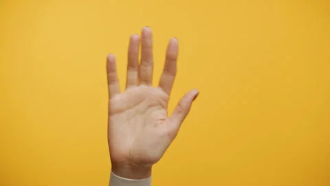 Waving Hand Gesture on Yellow Background | Stock Video | Pond5