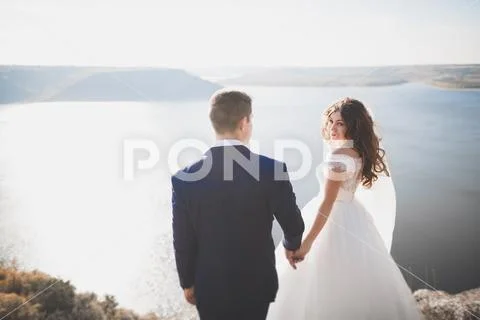 Wedding couple kissing and hugging on rocks near blue sea Stock Photo ...