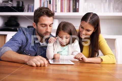 Which one do you want daddy. A little girl playing on a tablet with her ...
