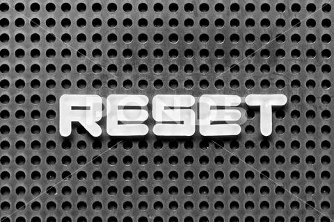 White alphabet letter in word reset on black pegboard background ...