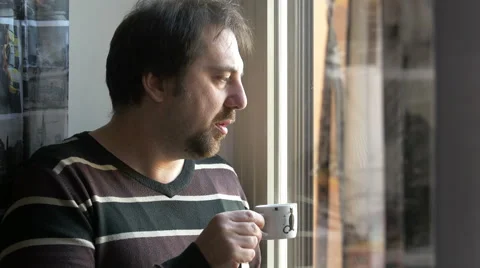 White man looks trough the window sippin... | Stock Video | Pond5