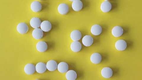 White round tablets on yellow background... | Stock Video | Pond5