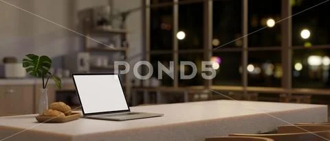 A white-screen laptop mockup on a modern white dining table in a ...