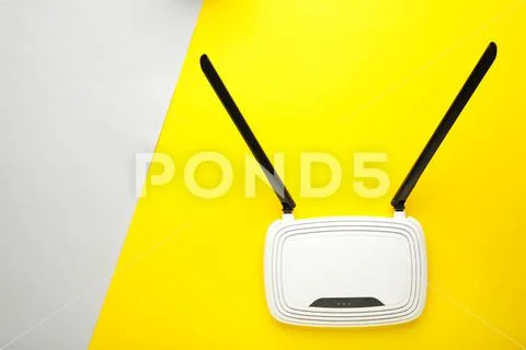 Photograph: White wi-fi router with black antennas on yellow grey ...