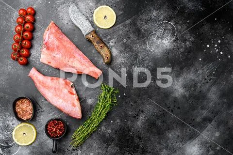Photograph: Whole raw red snapper fish, on black dark stone table ...