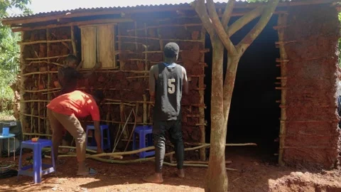 Wide shot of Africans packing mud onto t... | Stock Video | Pond5