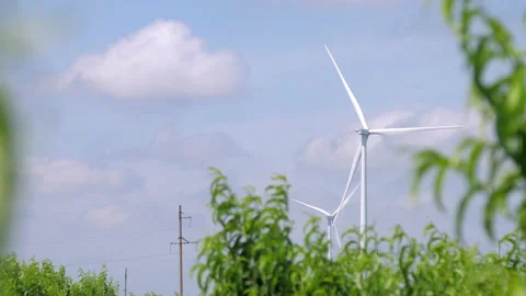 Wind machines rotate near power lines be... | Stock Video | Pond5