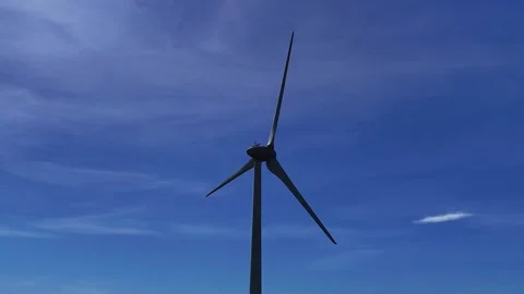Wind turbine spinning under a bright blu... | Stock Video | Pond5