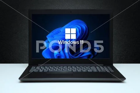 Windows 11 logo on the screen laptop computer black textured wall with ...