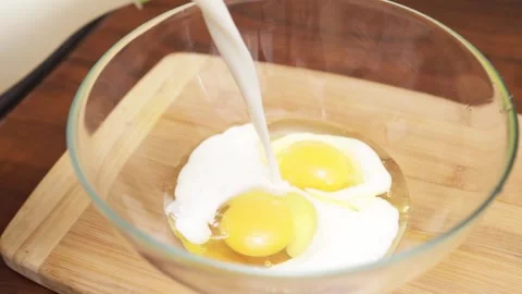 woman adding milk to eggs in bowl,cookin... | Stock Video | Pond5