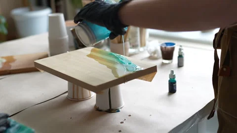 Woman artist pours epoxy resin and smear... | Stock Video | Pond5