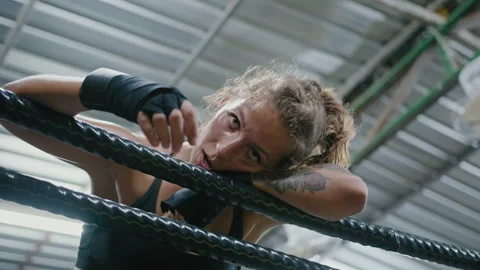 Woman boxer relaxes leaning on ring rope... | Stock Video | Pond5