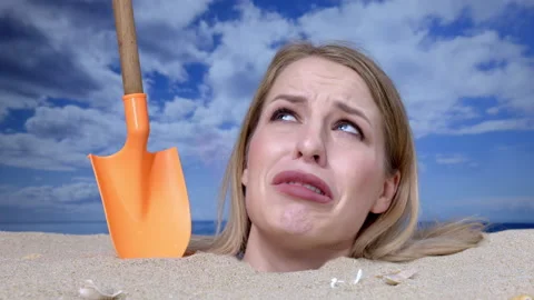 Woman buried in sand on beach with spade | Stock Video | Pond5