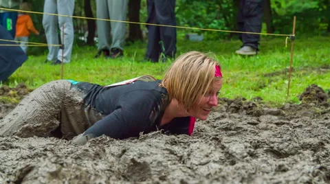Woman crawling through mud as part of ob... | Stock Video | Pond5