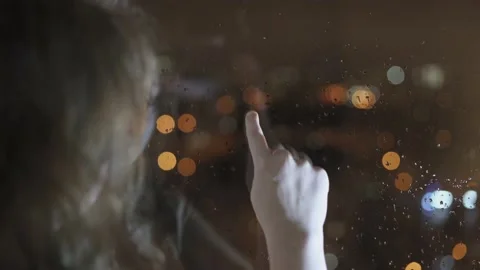 Woman draws with finger on wet window dr... | Stock Video | Pond5