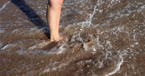 Woman feet step on sea wave on shore | Stock Video | Pond5