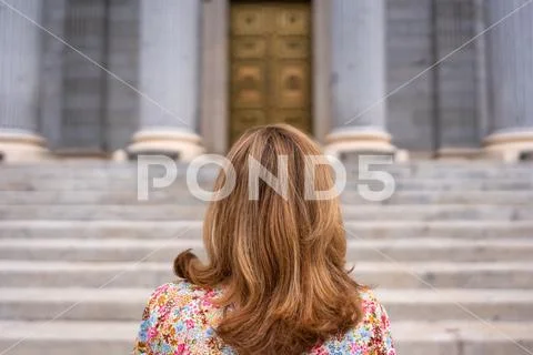 Woman with her back turned in front of the stairs of the main facade of ...