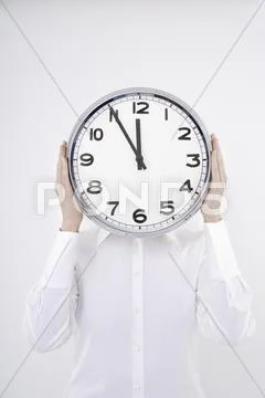 Woman holding clock in front of face ~ Hi Res #27059848