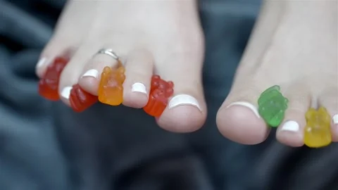 Woman holds gummy bears between toes wea... | Stock Video | Pond5